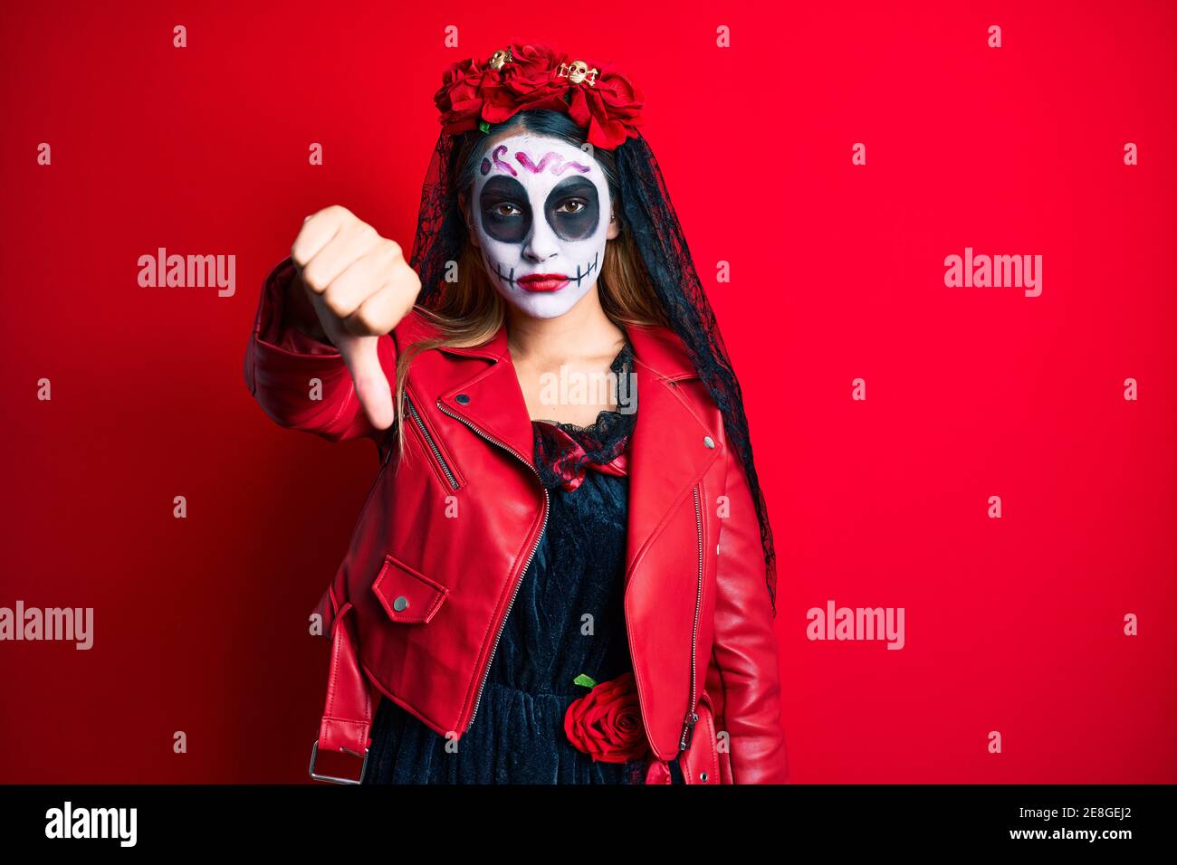 Woman wearing day of the dead costume over red looking unhappy and ...