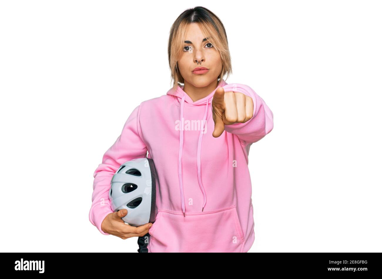 Young caucasian woman holding bike helmet pointing with finger to the ...