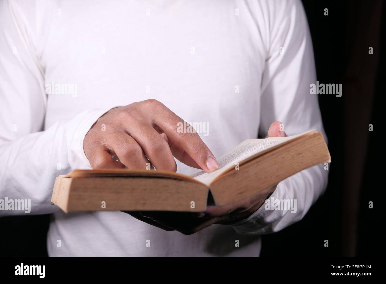 hand holding a book on black background Stock Photo - Alamy