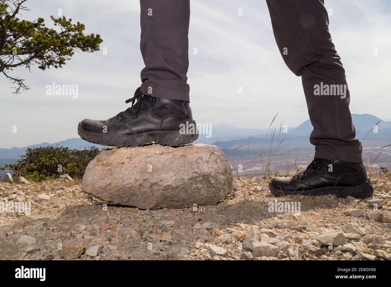 A hiker putting his foot on a rock climbing a mountain Stock Photo - Alamy
