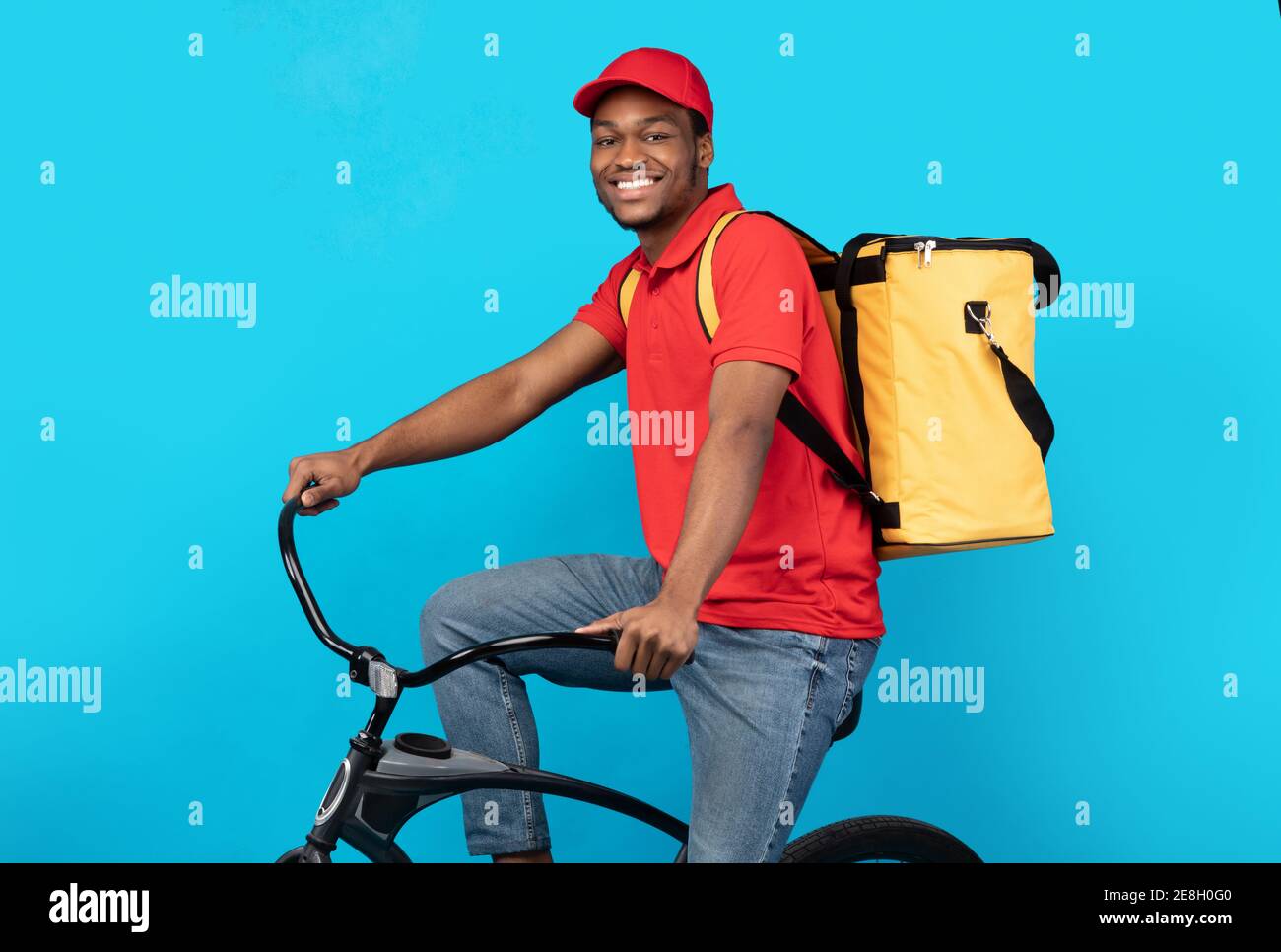 Smiling delivery delivery man riding bicycle at studio Stock Photo - Alamy