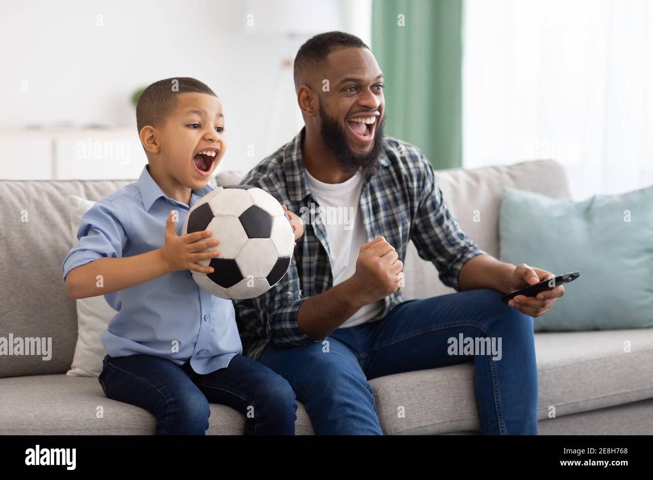 Joyful African Dad And Son Watching Sports On TV Indoors Stock Photo ...