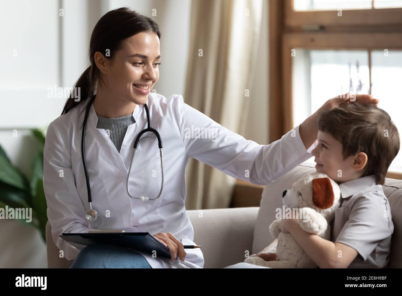 Smiling female doctor cheer small boy patient Stock Photo - Alamy