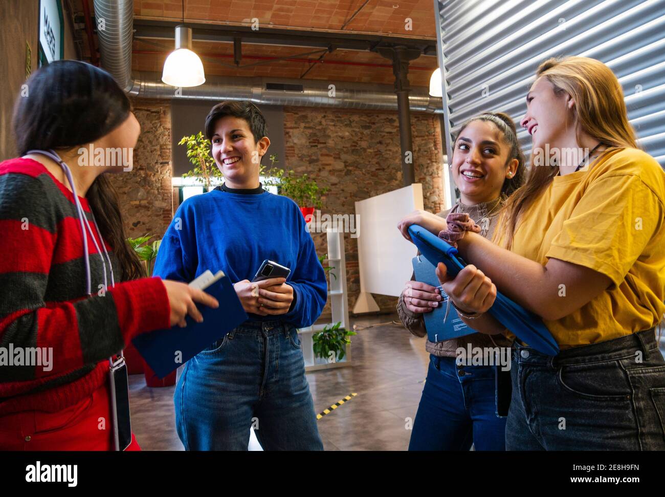 Young female classmates in casual wear standing close while talking ...