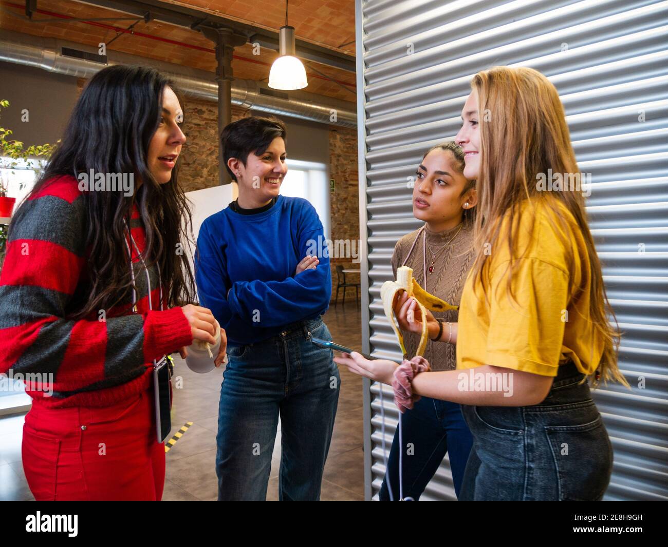 Young female classmates in casual wear standing close while talking ...
