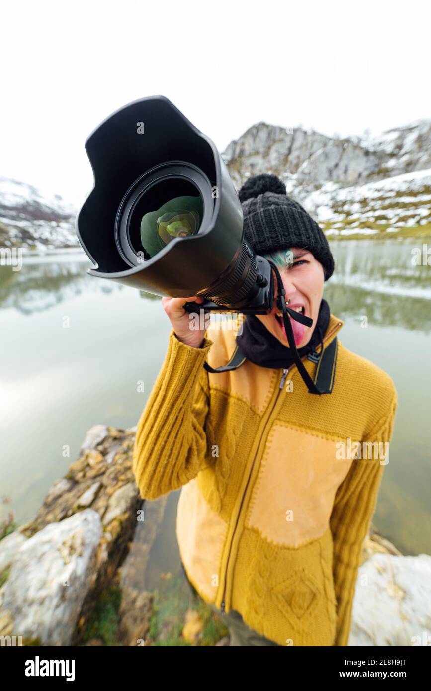 Female photographer wearing warm clothes and hat shooting pictures and ...