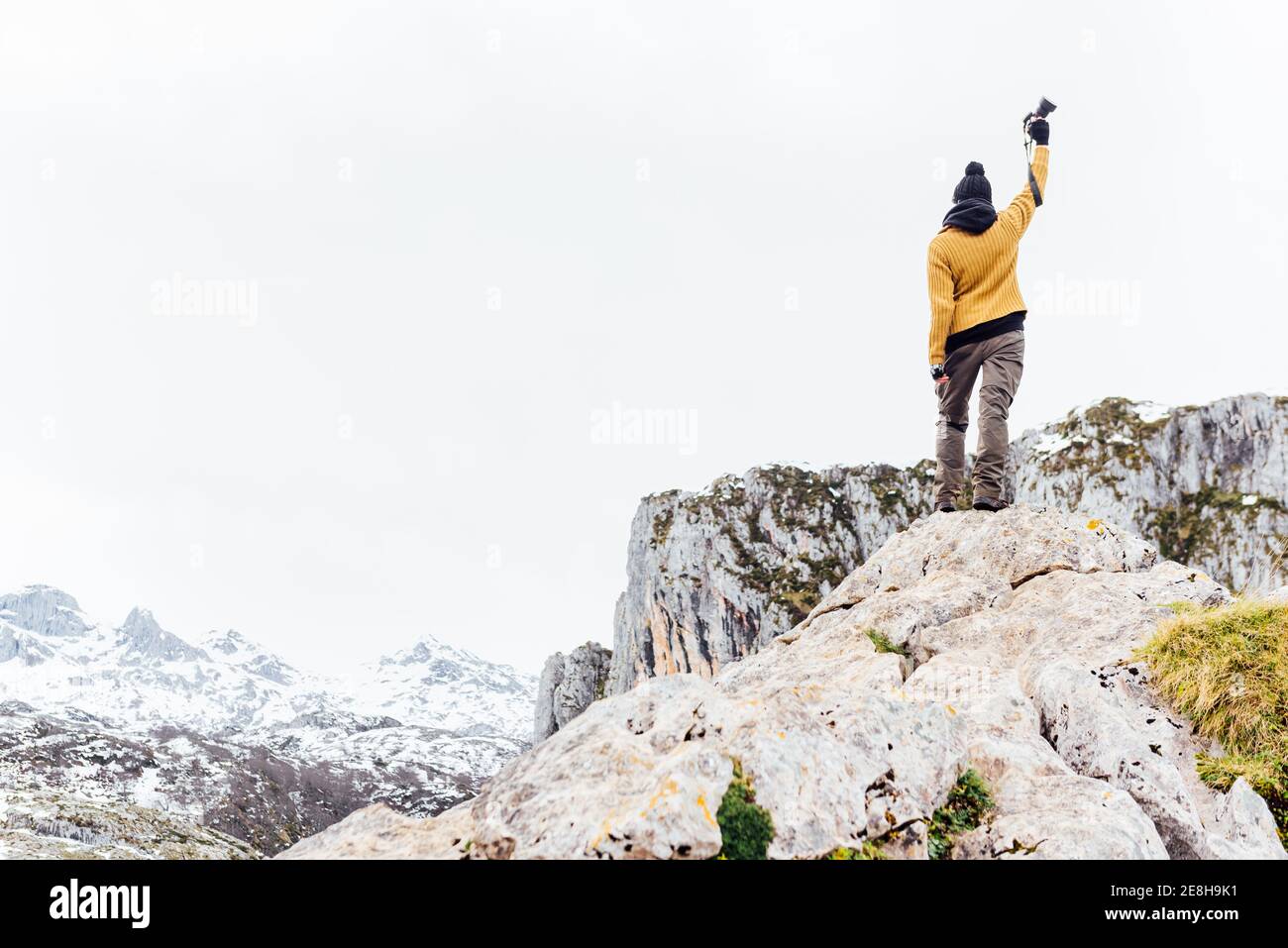 Back view full body photographer in warm clothes raising arm with photo ...