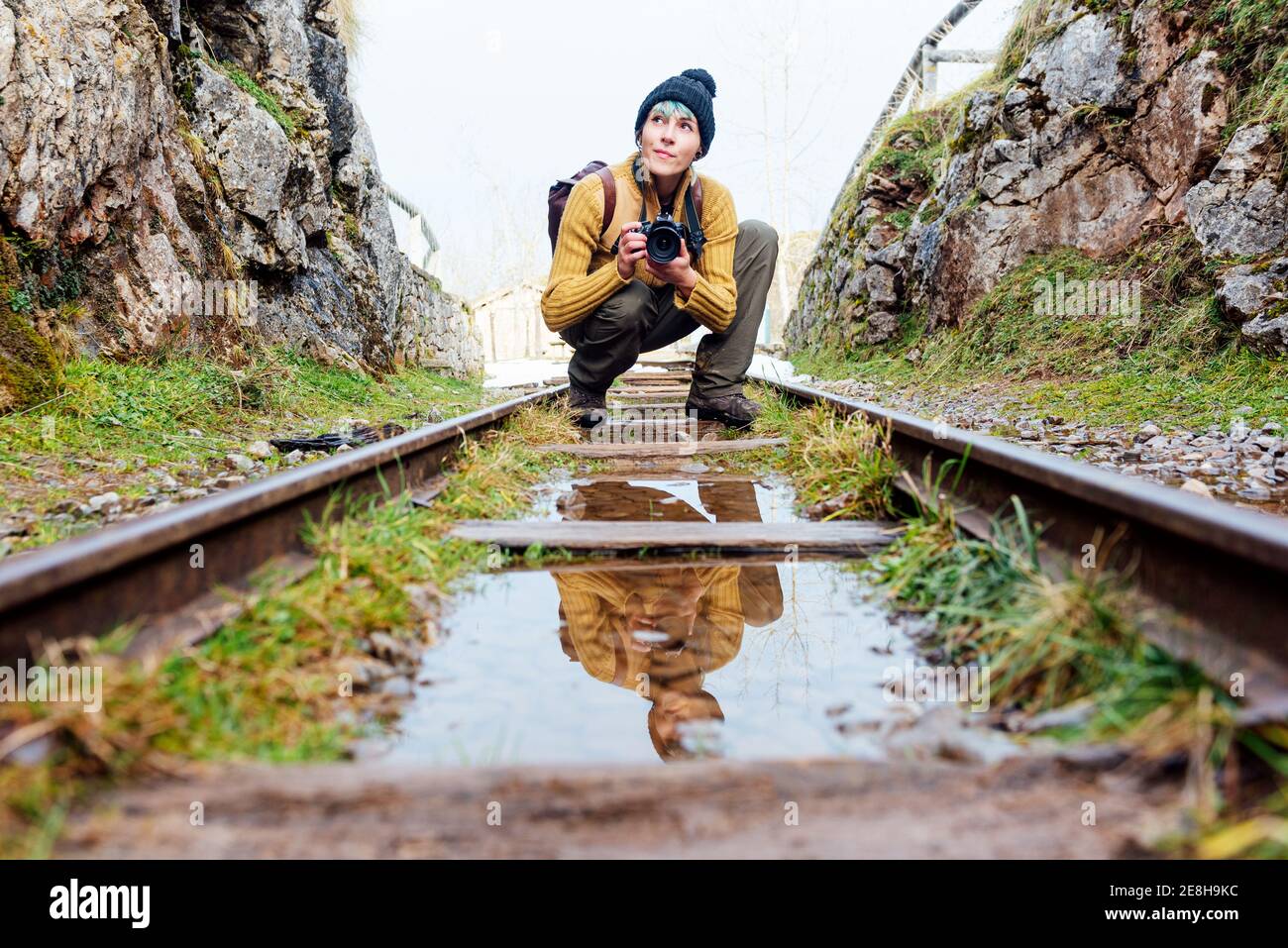 Full body young female photographer in warm sweater and hat sitting on ...