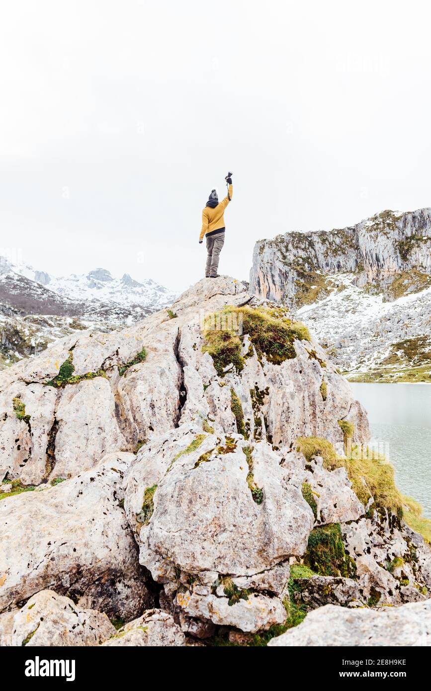 Back view full body photographer in warm clothes raising arm with photo ...