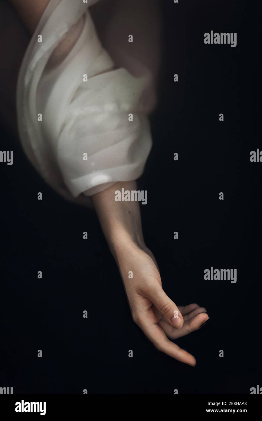 From above crop slim female hand in wet white translucent sleeve ...