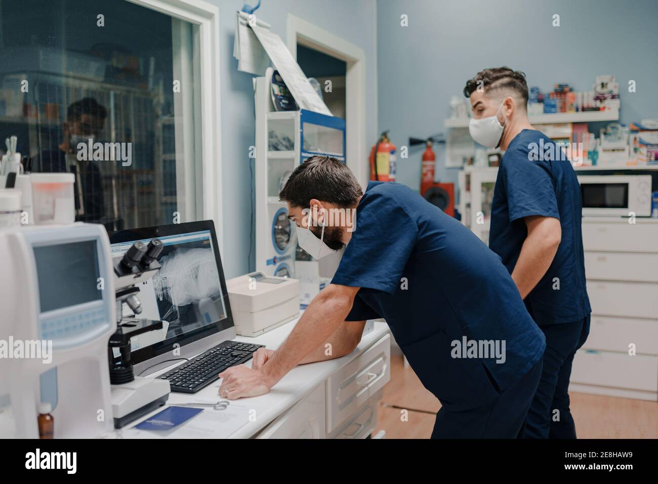 Anonymous young male doctors in respiratory masks and uniforms working ...