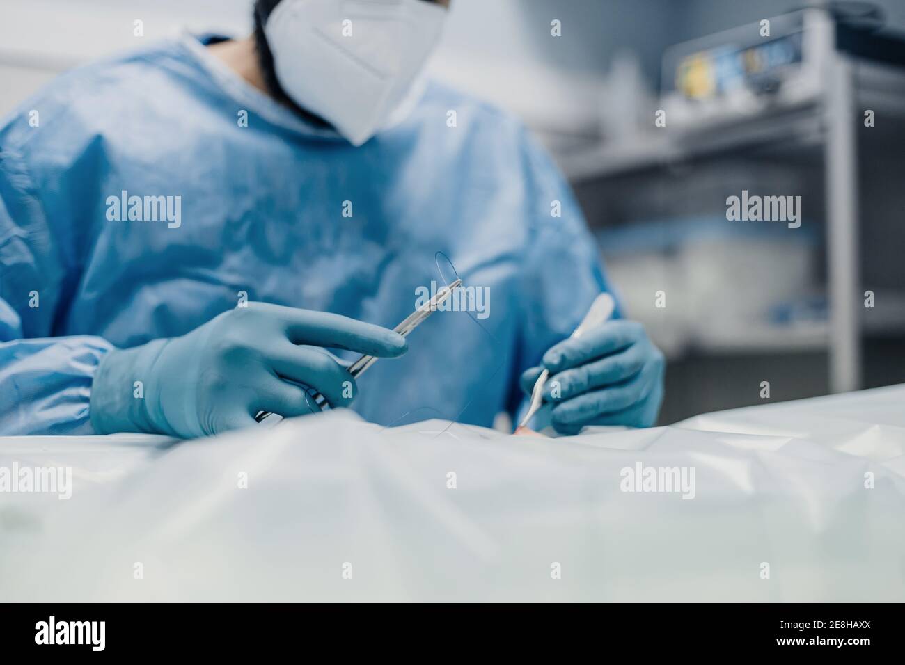 Crop anonymous male veterinarian in uniform and respiratory mask using ...