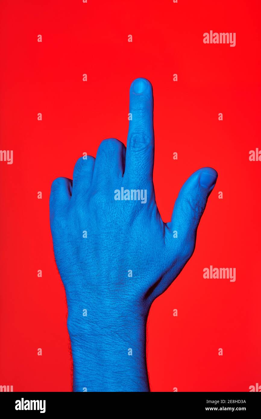 man's blue hand pointing whit his finger over red background. Isolated ...