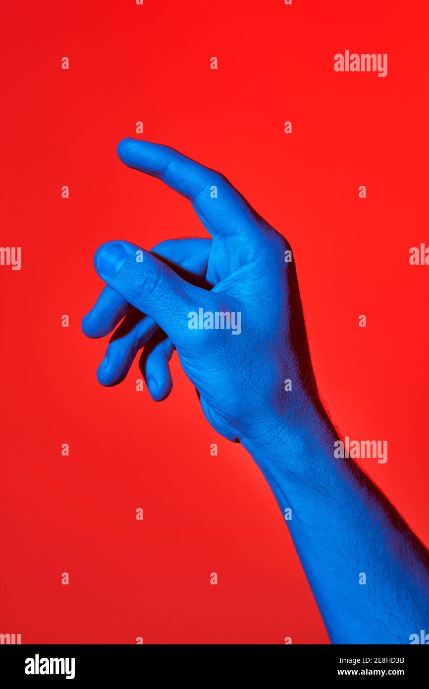 man's blue hand pointing upwards over red background. Isolated vertical ...