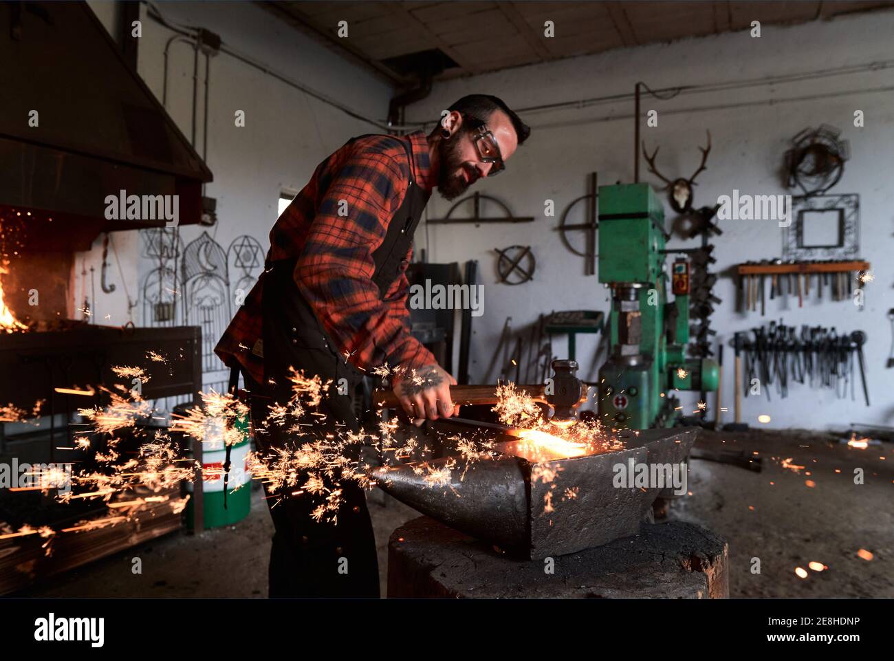 Side view of young brutal bearded craftsman in apron and goggles ...