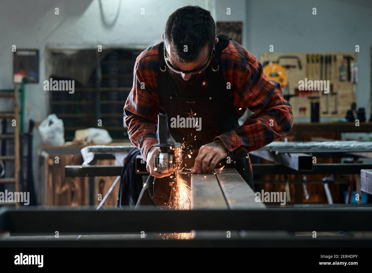 Front view of unrecognizable young male blacksmith in protective ...