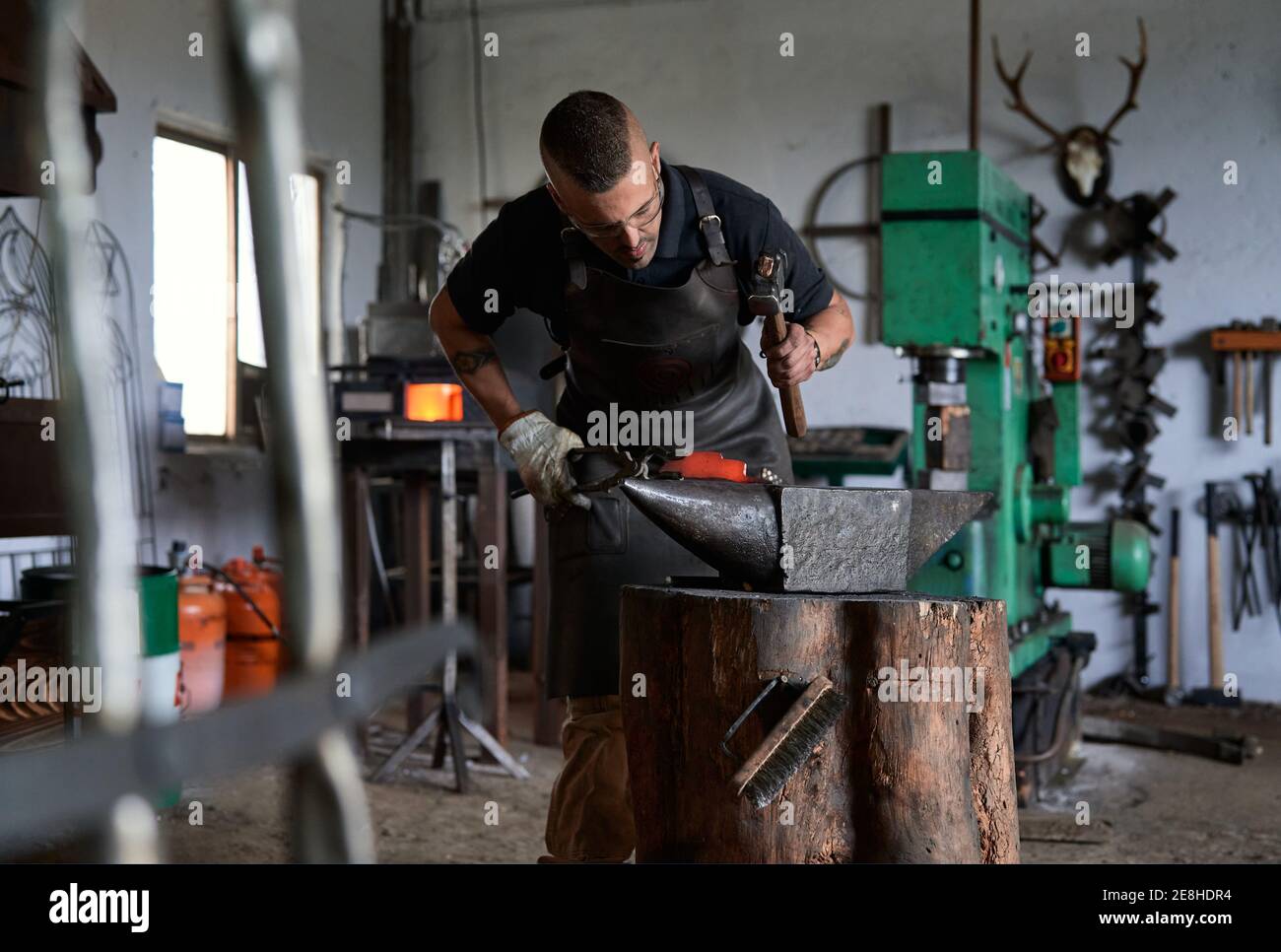 Front view of concentrated young male blacksmith in casual clothes and ...
