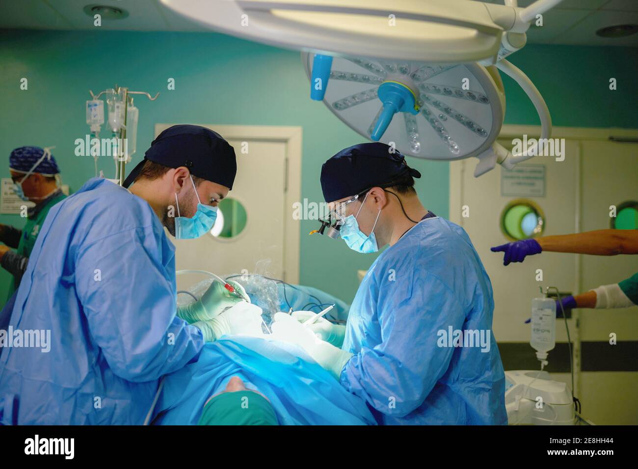 Side view of unrecognizable male doctor with assistant in medical gowns ...
