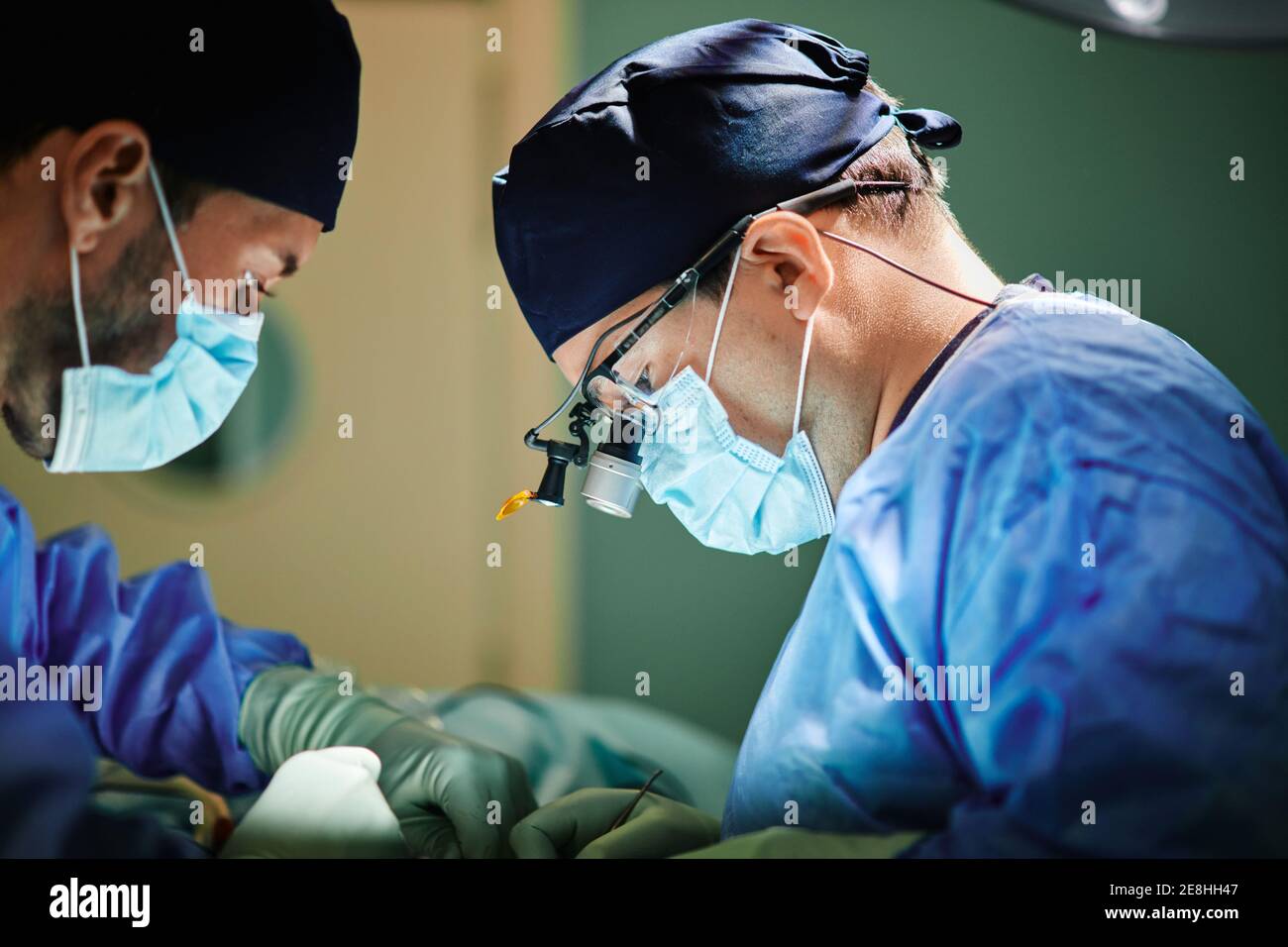 Side view of unrecognizable male doctor with assistant in medical gowns ...
