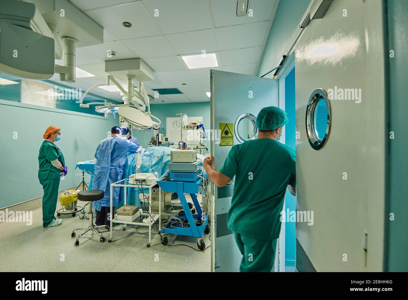 Back view of unrecognizable medical assistant leaving operating room ...