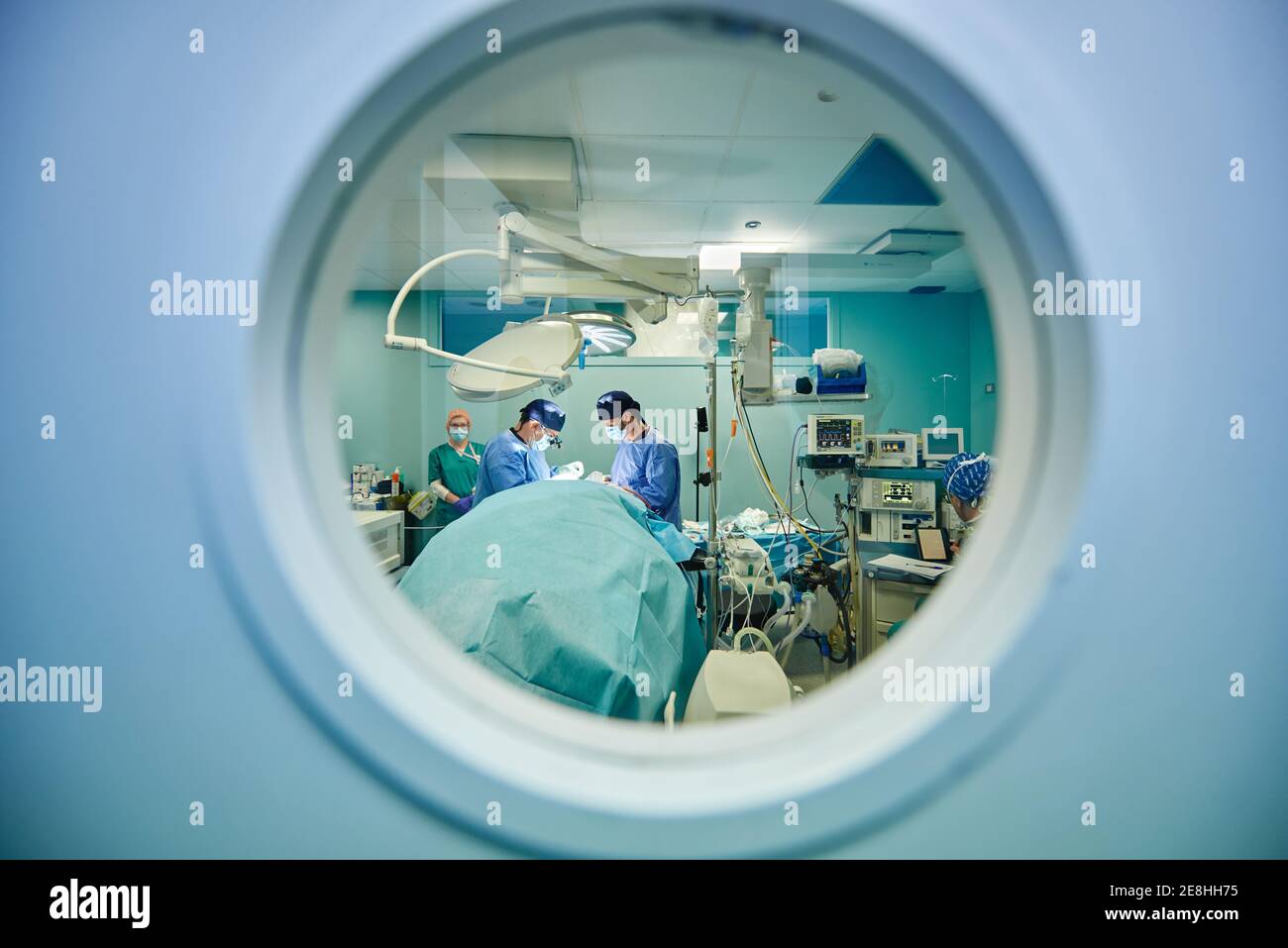 Through round window of unrecognizable doctors in uniforms and masks ...