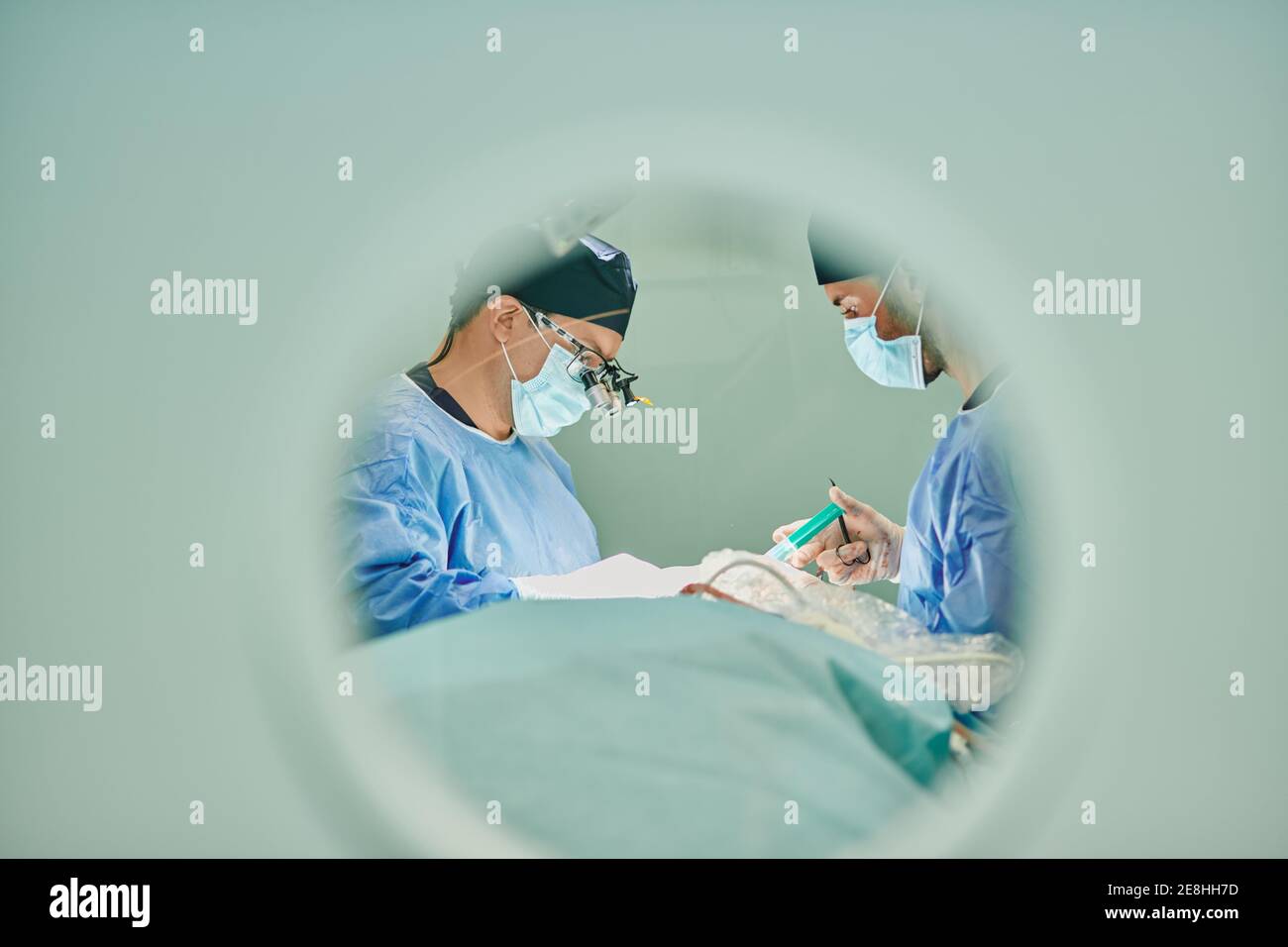 Through round window of unrecognizable doctors in uniforms and masks ...