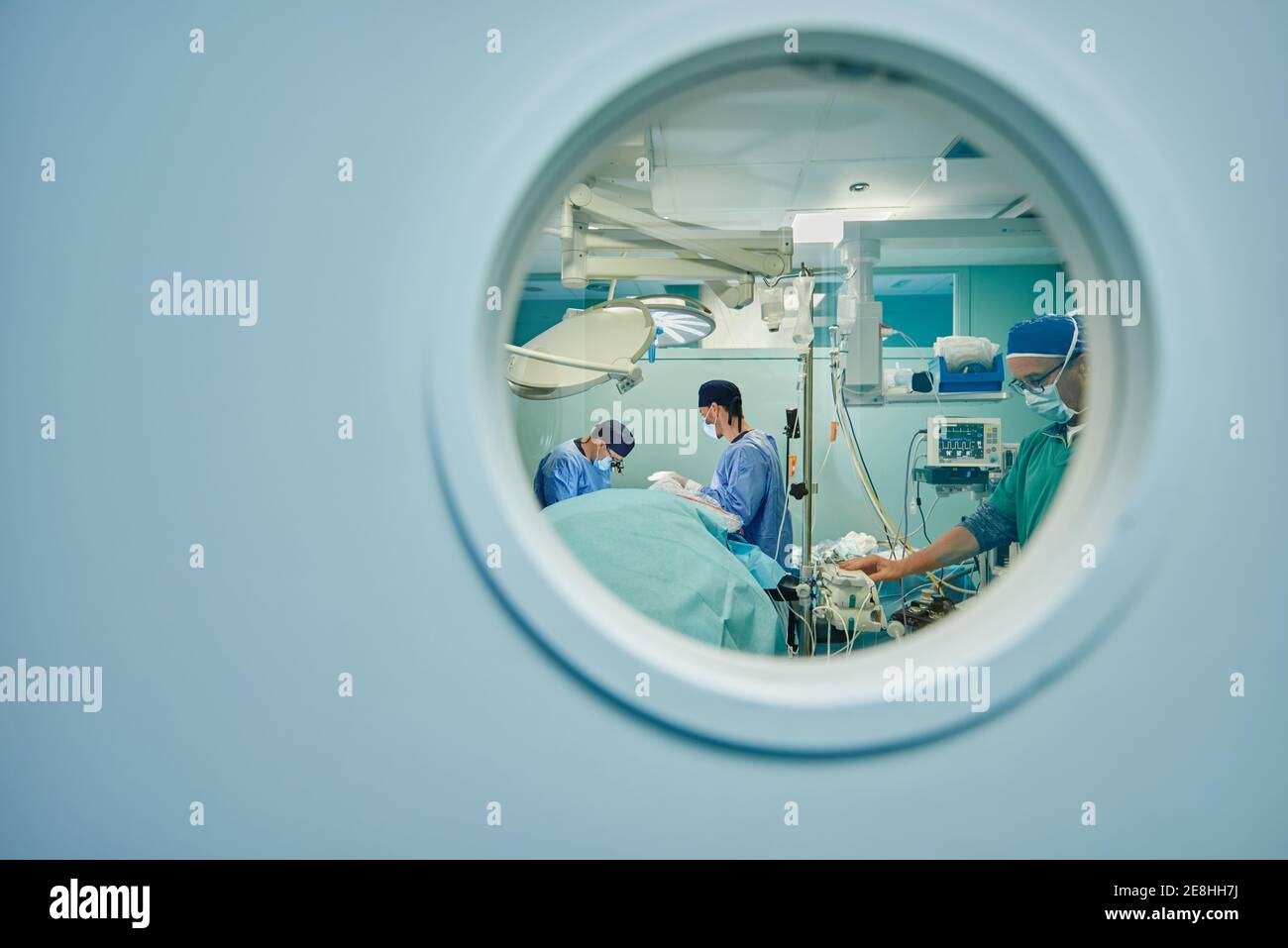 Through round window of unrecognizable doctors in uniforms and masks ...
