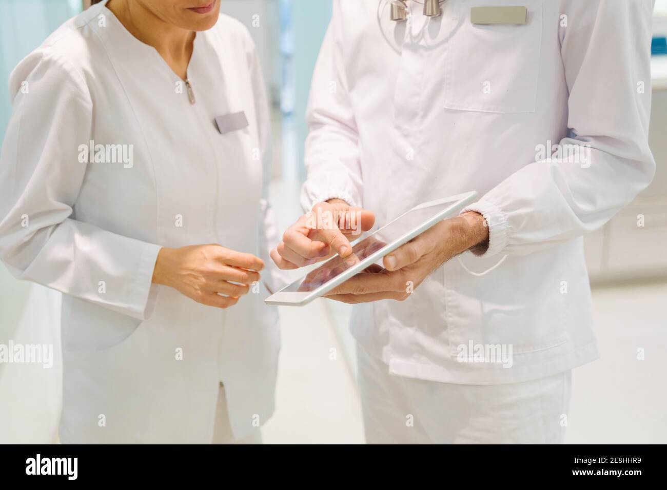 crop anonymous dentists in medical robes examining teeth condition on x ...