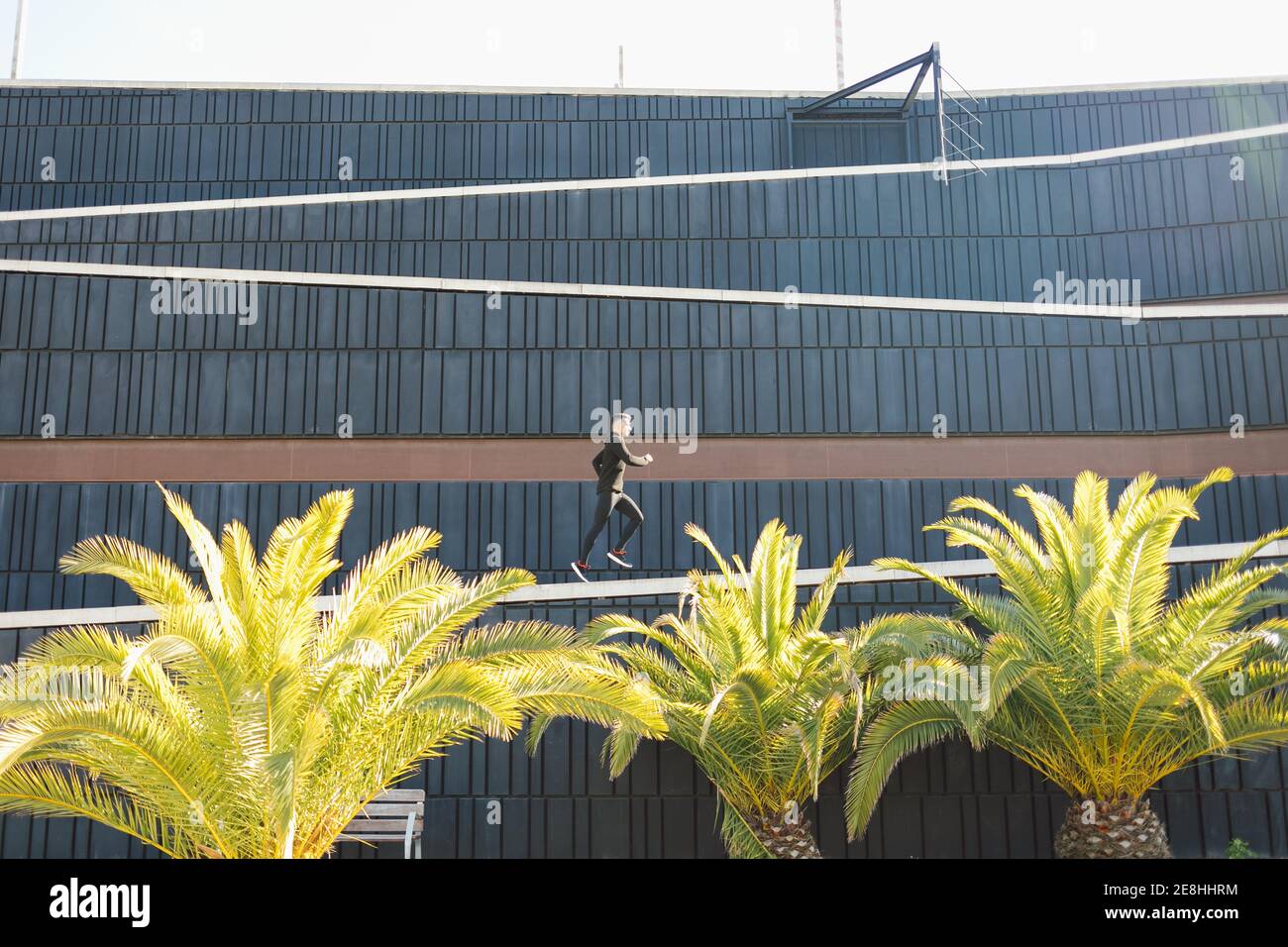 Side view full body sporty fit man in activewear jogging on footpath on ...