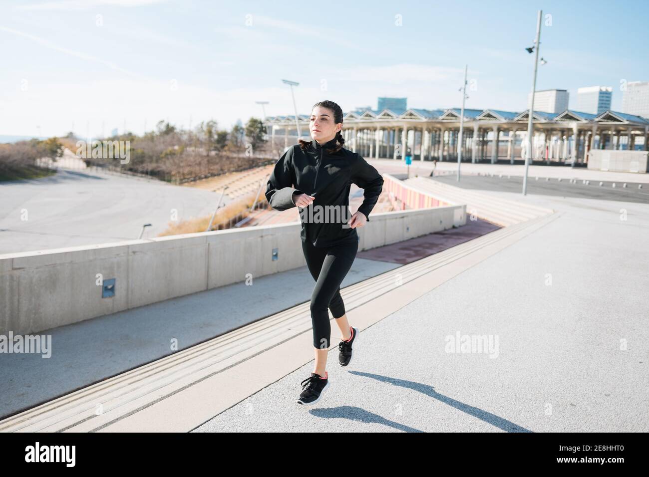 Full body sporty young female jogger in black activewear running on ...