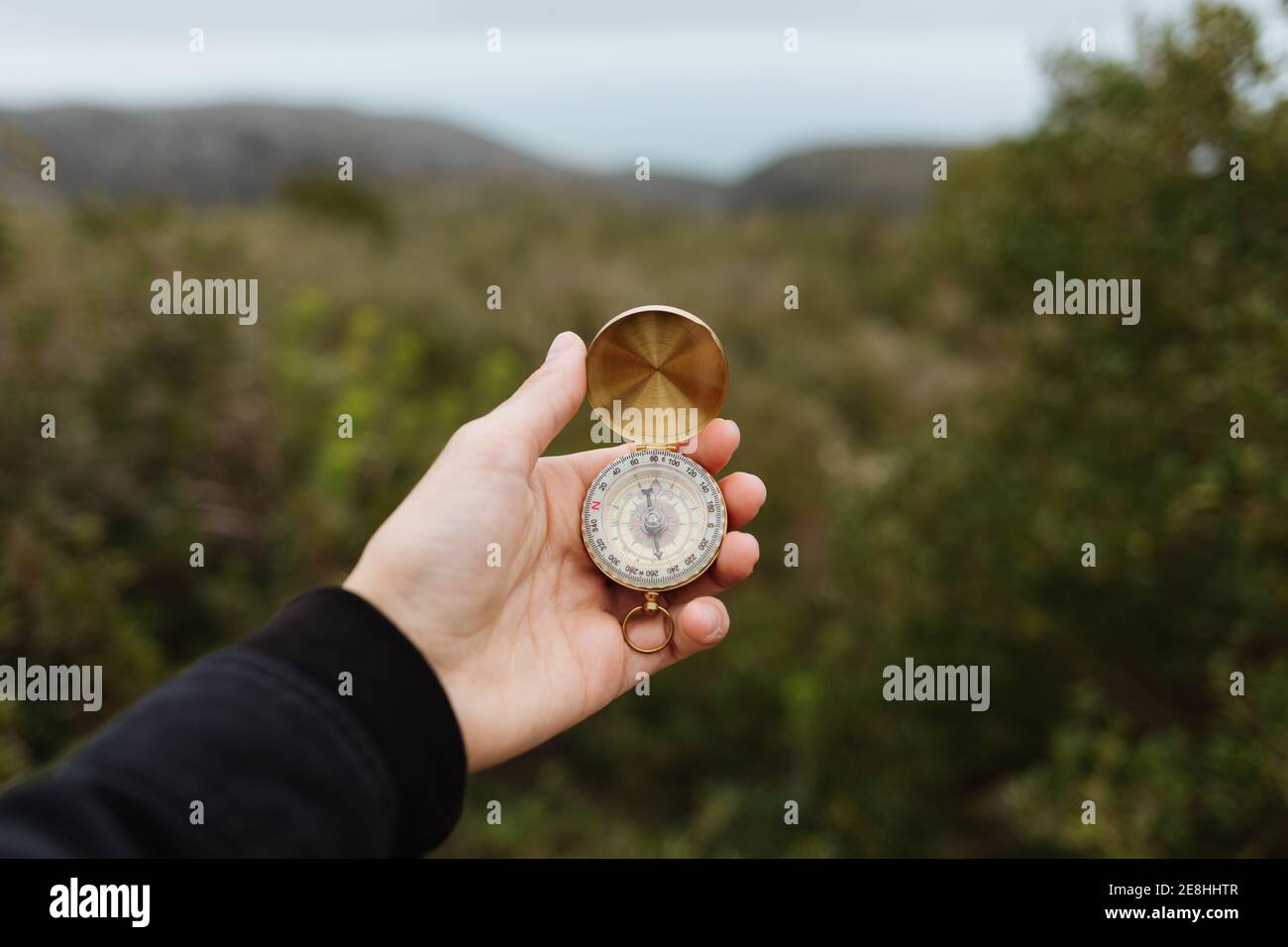 crop anonymous person tourist using compass on mountain with rough ...