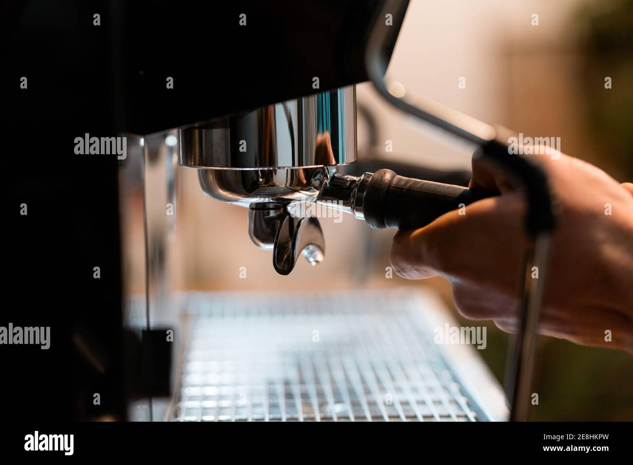 Crop anonymous barista using portafilter in coffee machine while ...