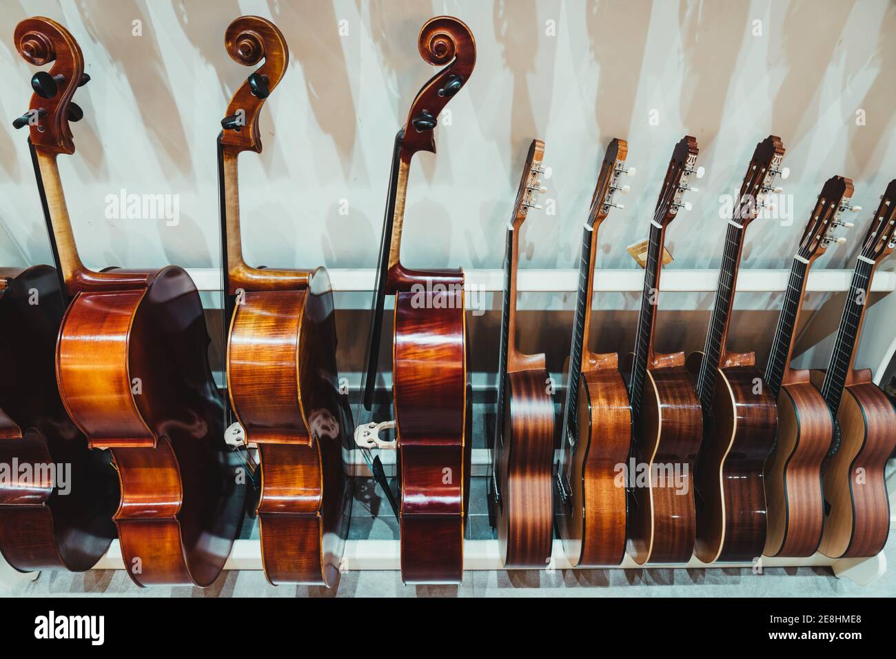 Collection of modern acoustic violins and guitars hanging on rack ...