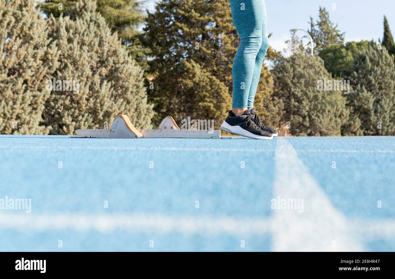 Ground level side view of runner standing on track near starting blocks ...