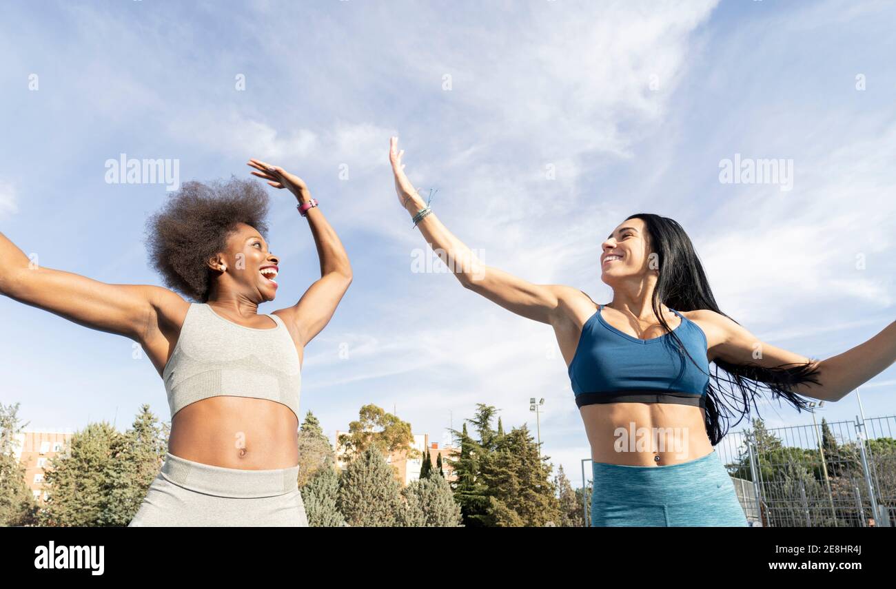 From below of delighted multiethnic female athletes in sportswear in ...