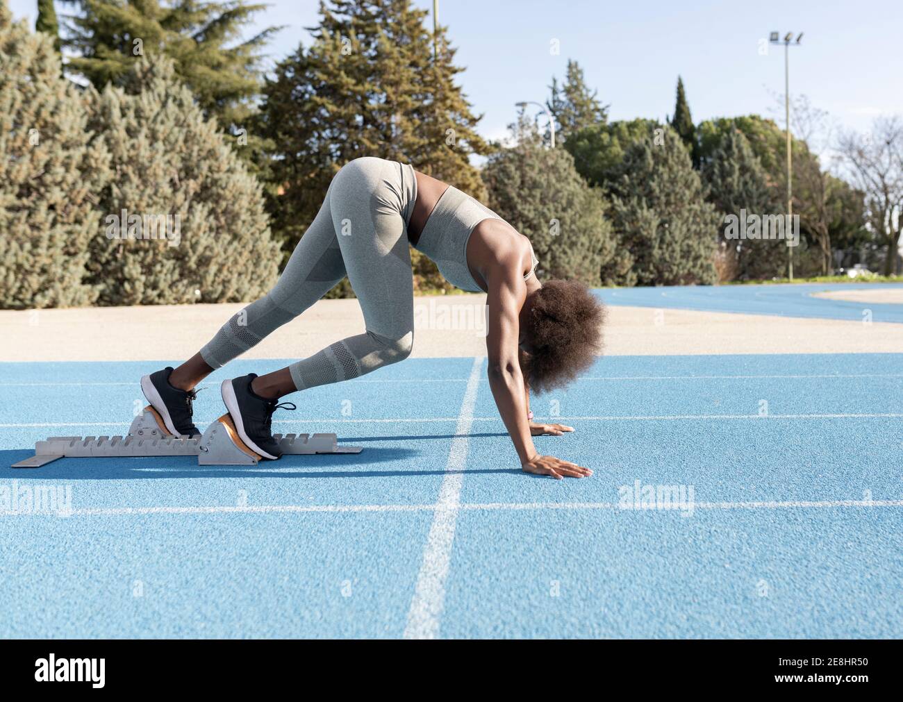 Side view of African American female runner in starting blocks standing ...