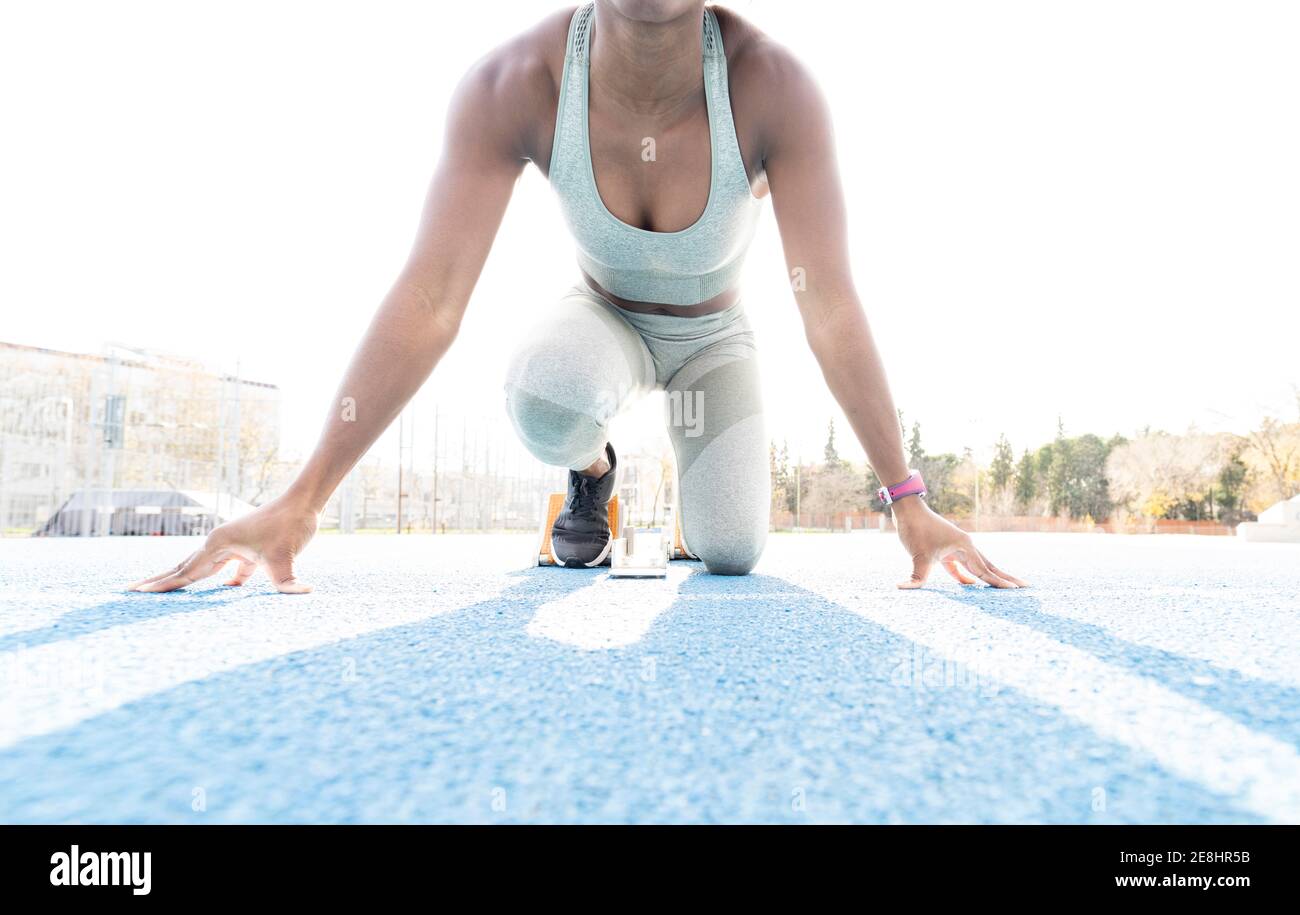 From below of African American female runner in starting blocks sitting ...