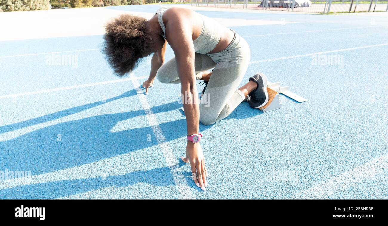 From above of African American female runner in starting blocks ...