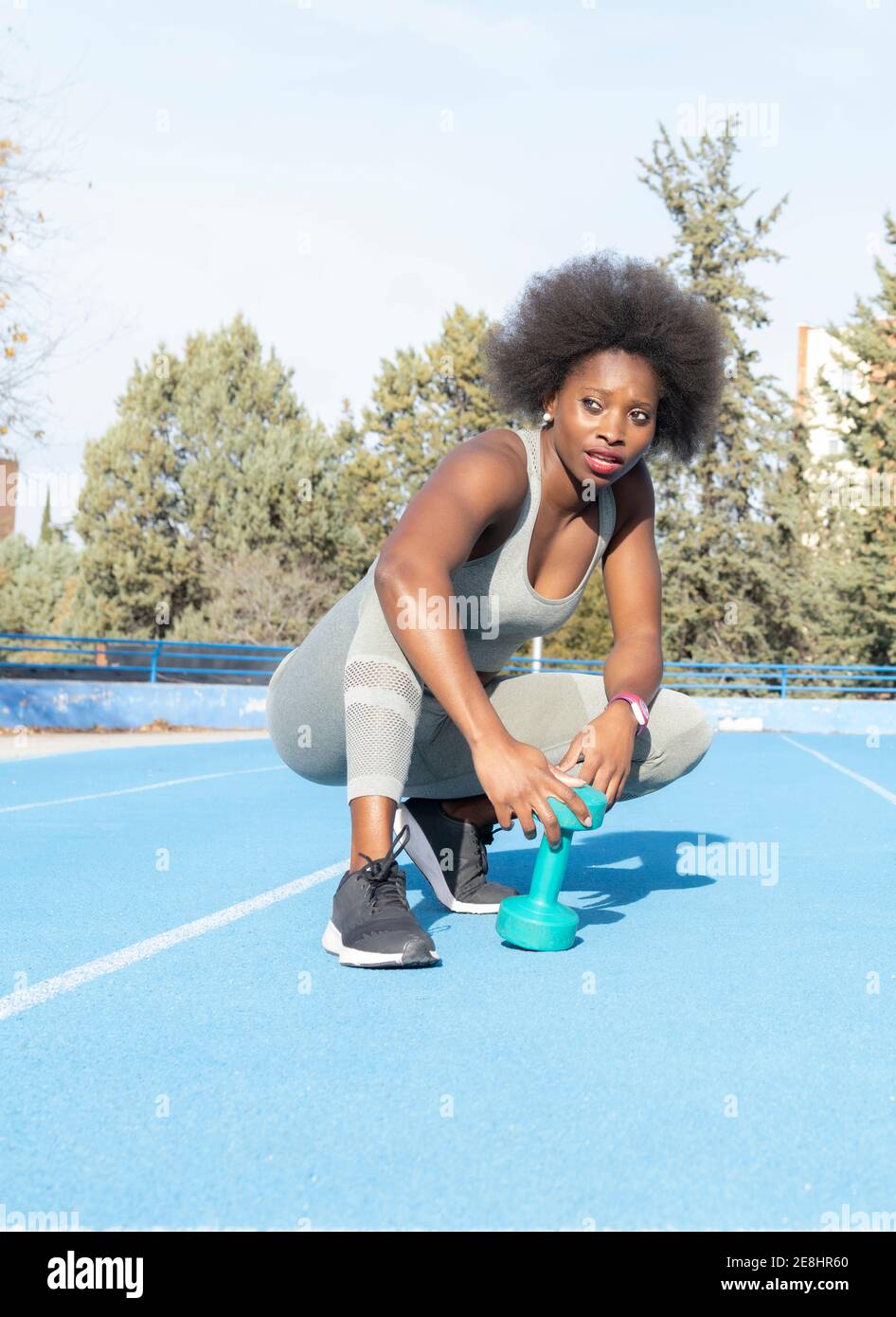 Focused black female athlete doing exercises with dumbbell while ...
