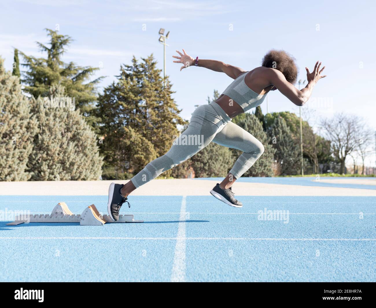 Side view of energetic African American female athlete running out of ...