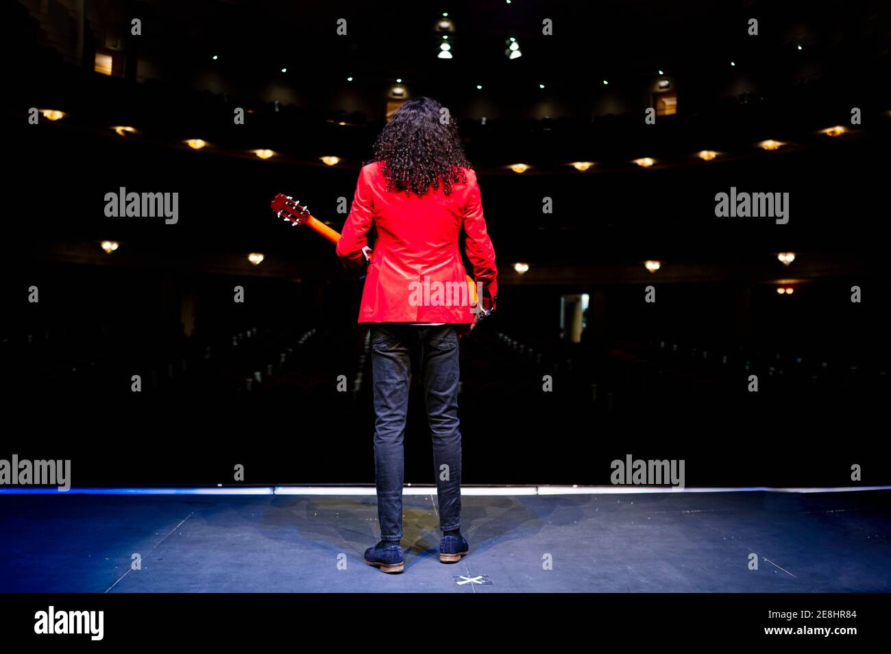 Full body of male musician standing on stage and playing guitar during ...