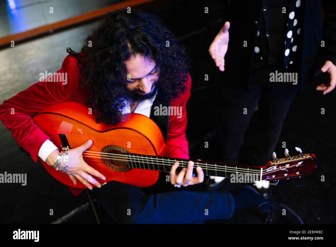 Ethnic male musician holding chord on strings of guitar while playing ...