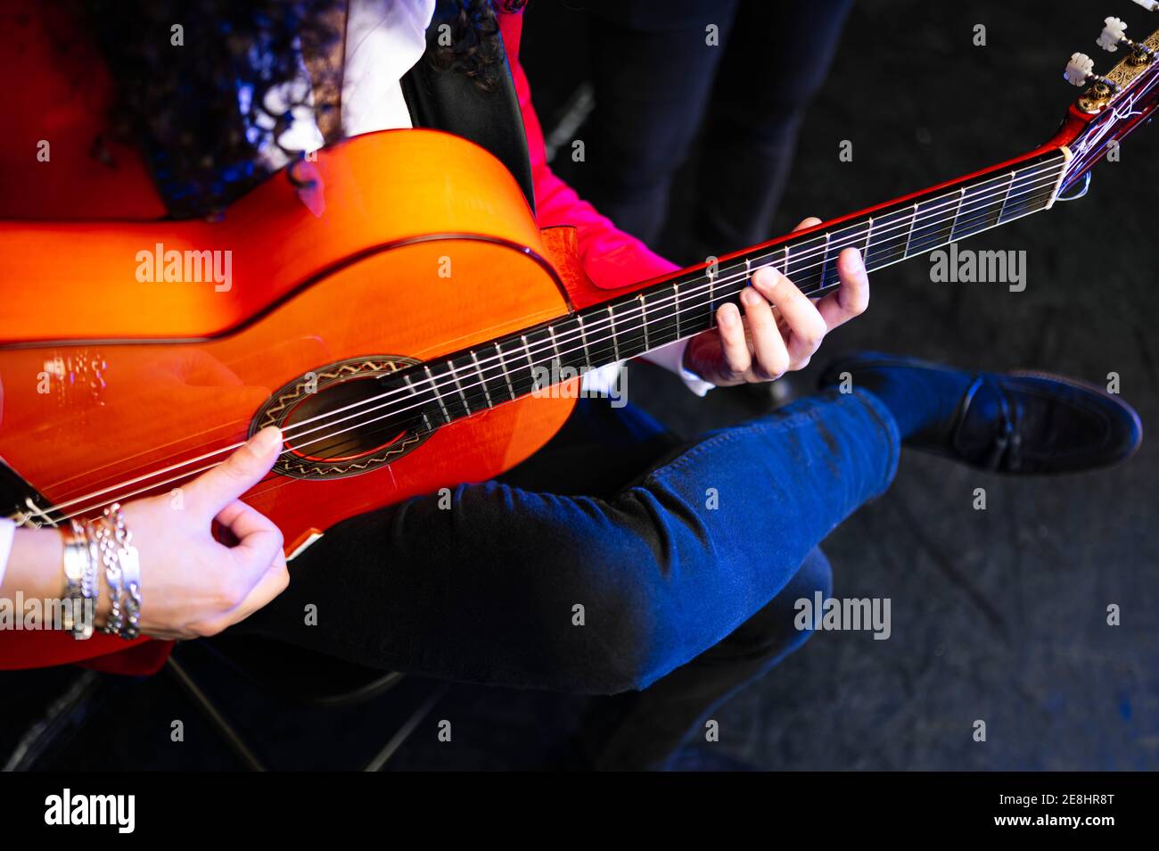 Ethnic male musician holding chord on strings of guitar while playing ...