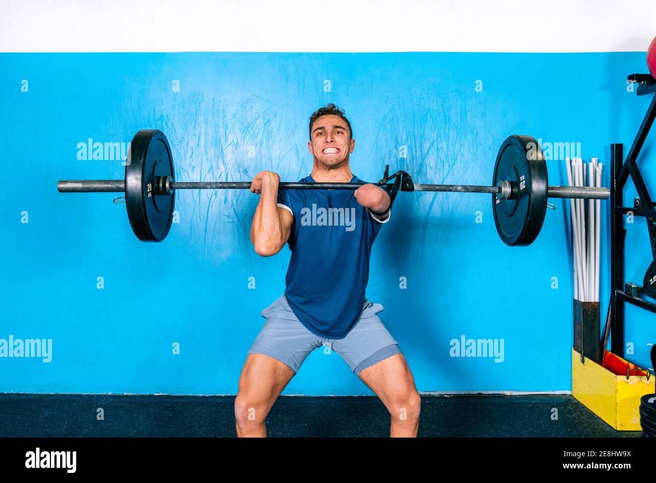 Powerful male athlete without hand screaming while lifting heavy weight ...
