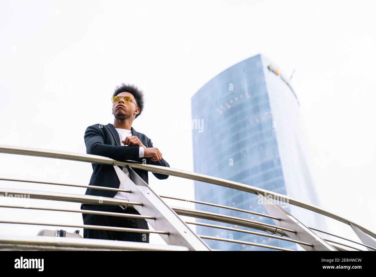 From below of confident African American male leaning on railing while ...