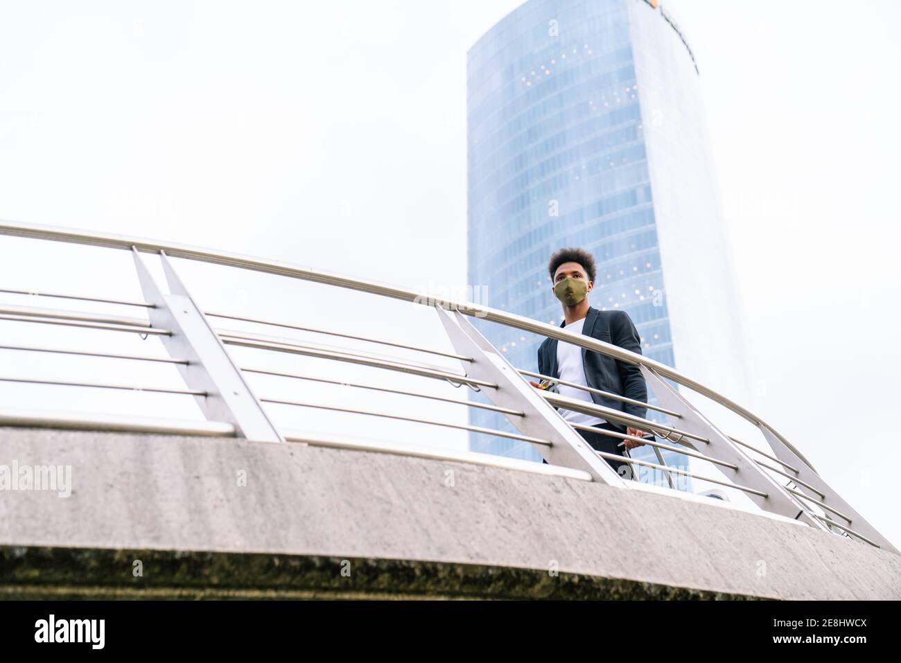 From below of confident African American male leaning on railing while ...