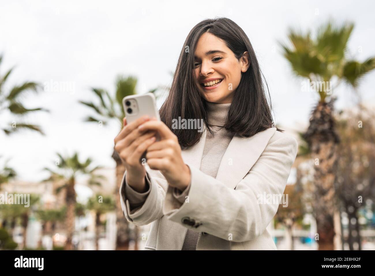Smiling charming female taking selfie on smartphone while standing in ...