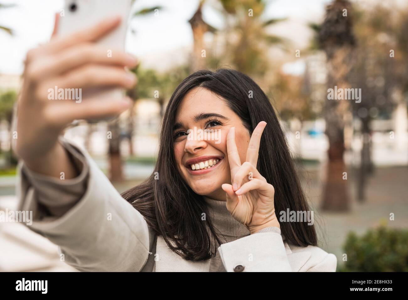 Smiling charming female taking selfie on smartphone while standing in ...