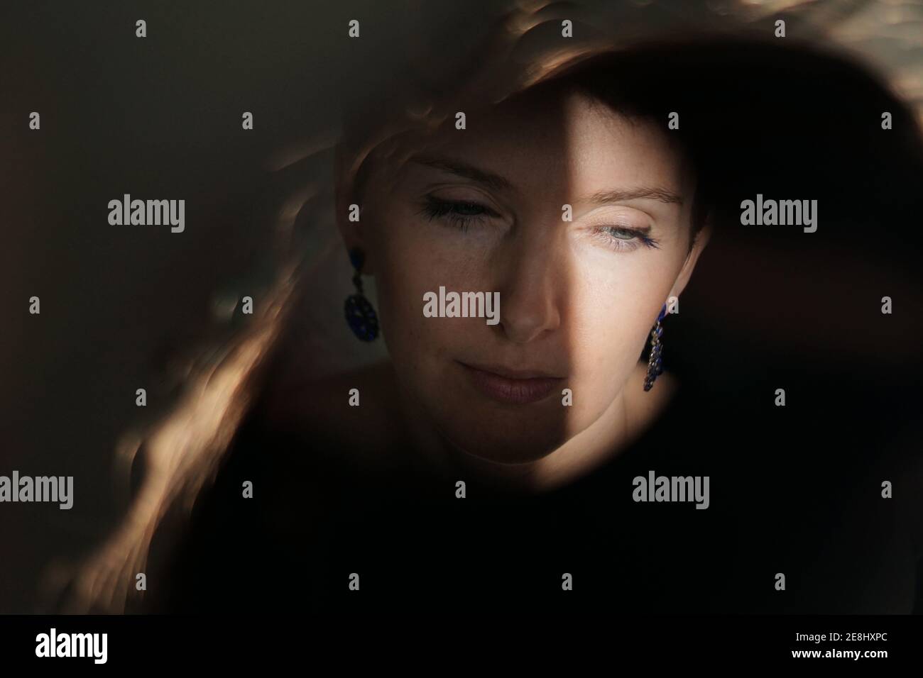 Through glass of peaceful thoughtful adult lady with short hair looking ...