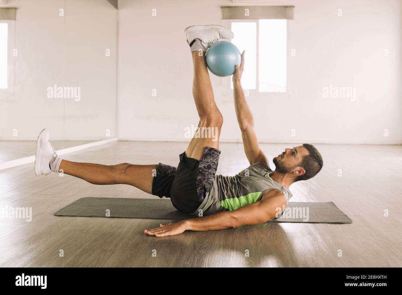 Side view of determined muscular young sportsman in activewear doing ...